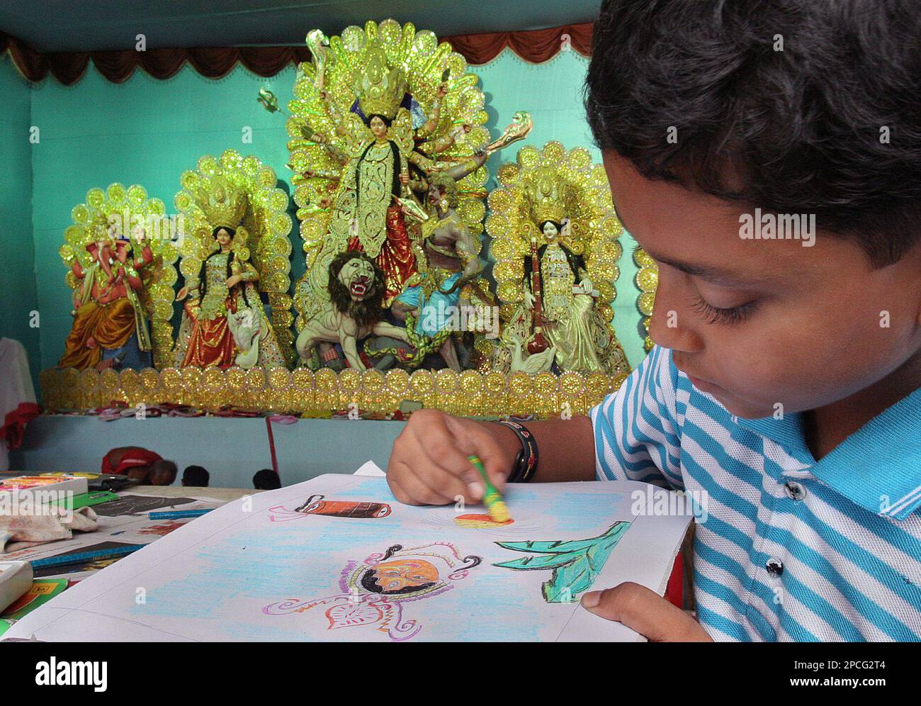 A boy sketches an image of Hindu Goddess Durga in a makeshift prayer ...