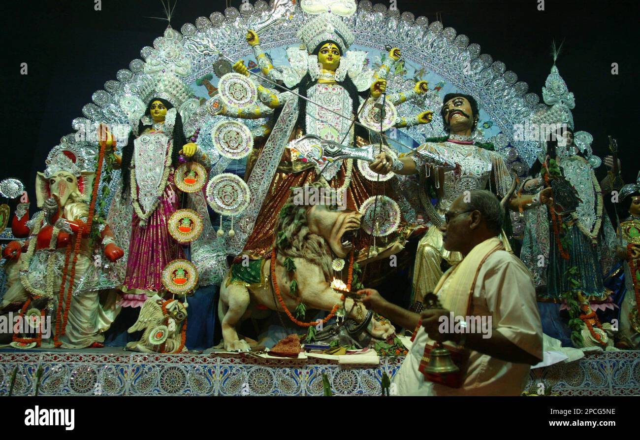 A Hindu priest performs a ritual in front of an idol of Goddess Durga ...