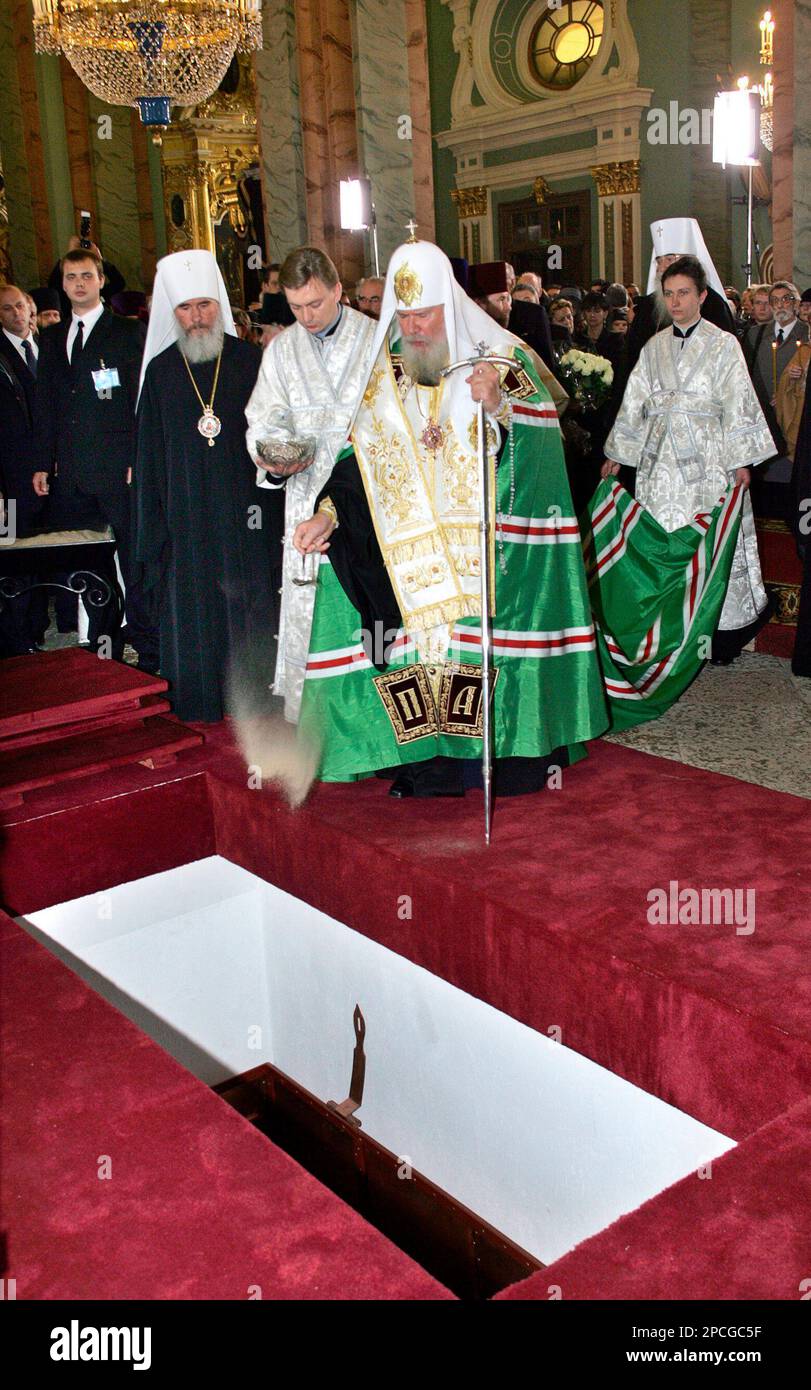Russian Orthodox Patriarch Alexy II throws a handful of soil on the ...