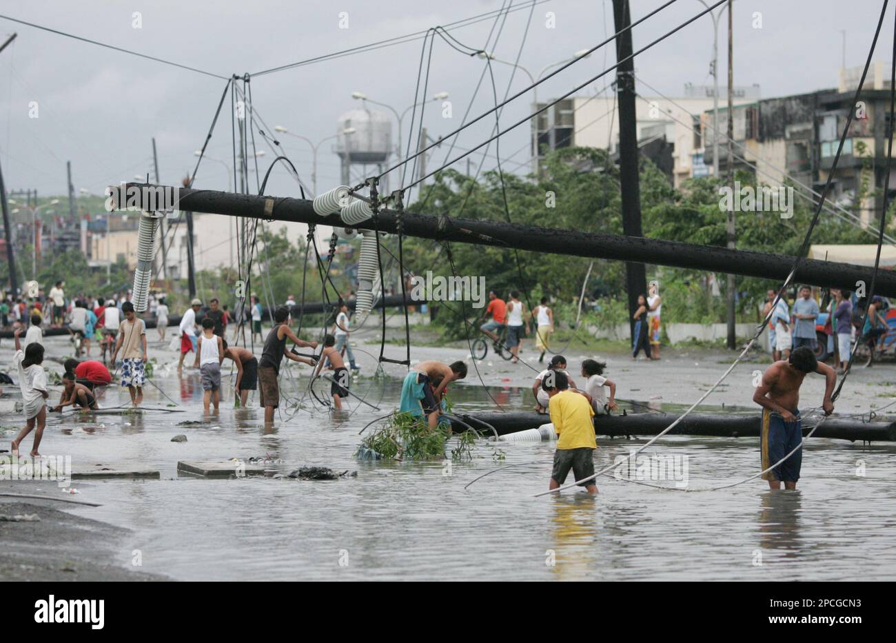 Residents from a poor Manila neighborhood cut the wires of toppled ...