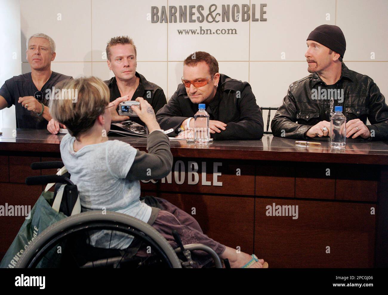 A fan takes a picture of the the rock band U2, left to right, Adam ...