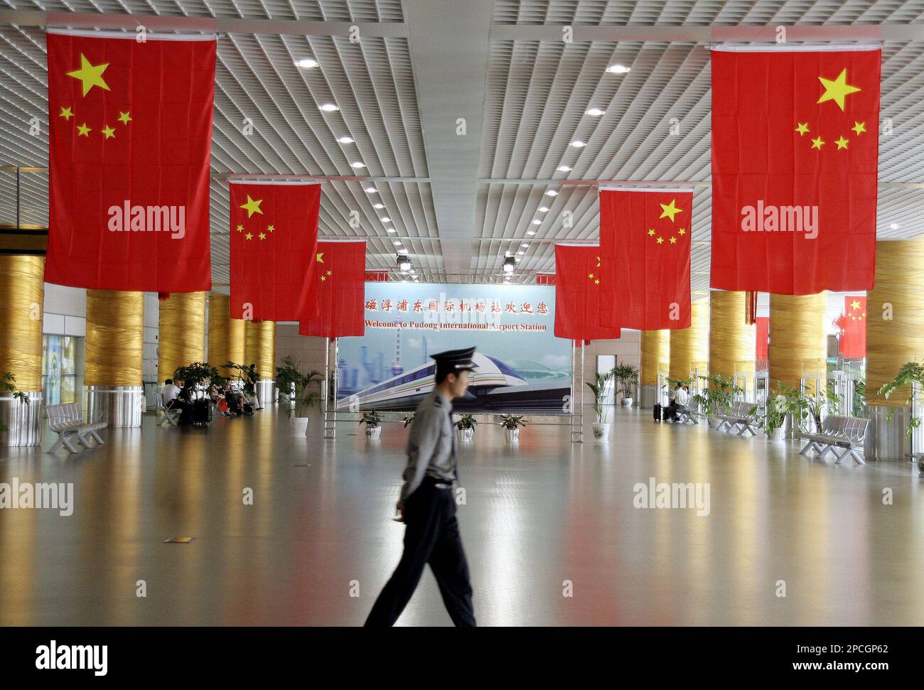 A security guard walks past Chinese national flags and maglev ...
