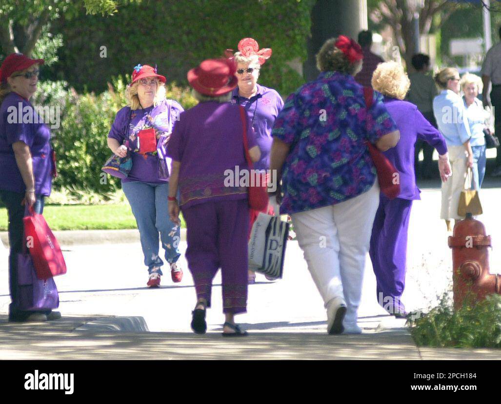 Women of the Red Hat Society pass each other while strolling through ...