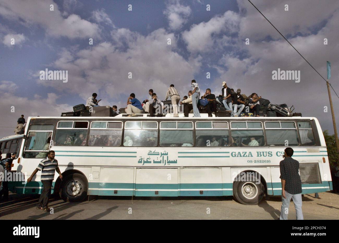 Palestinians sit on top of a bus as they wait to leave the Gaza Strip ...