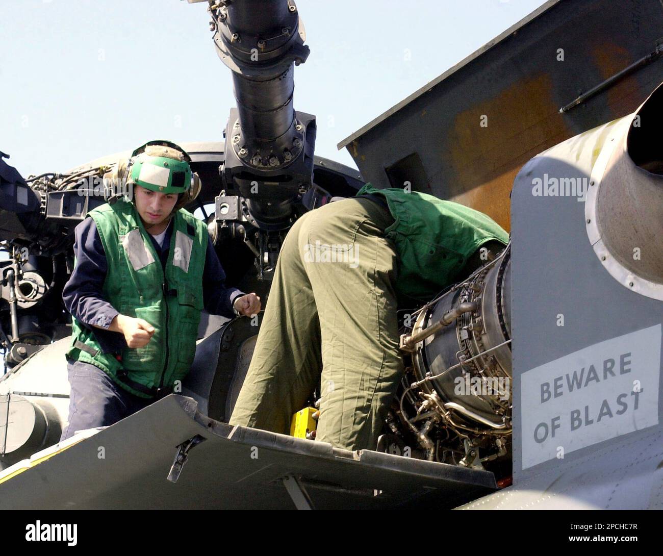 Crewmen aboard the USS Saipan check over a helicopter while U.S. Navy ...