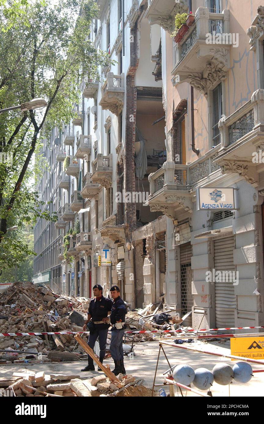 Policemen stand next to the debris from the collapse of an apartment ...