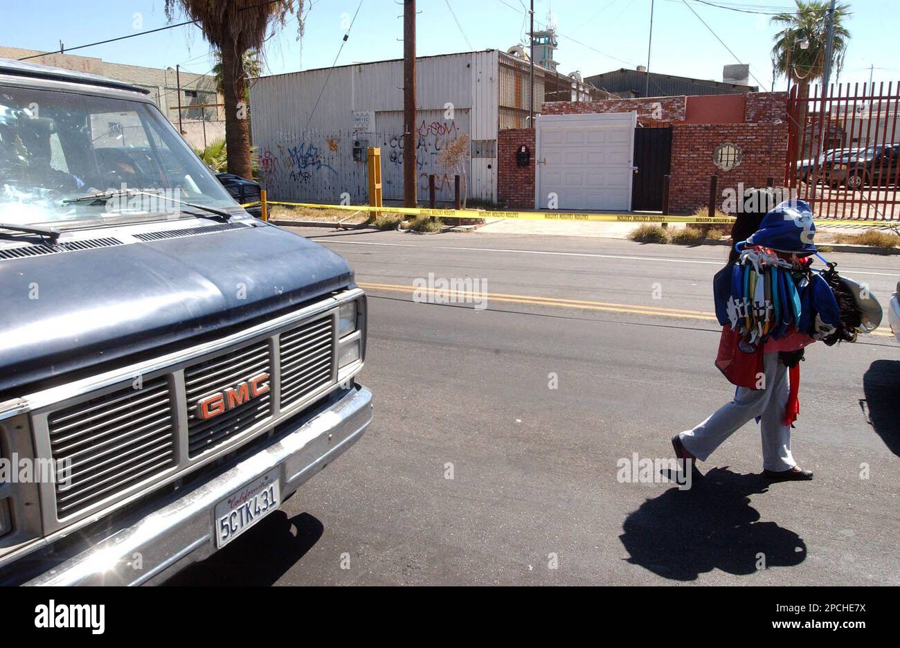 A street vendor walks past a house, background, in which a cross-border ...
