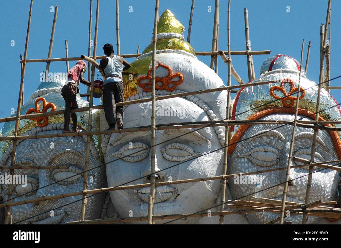 Workers paint a giant idol of Hindu God Narayana, at a makeshift prayer ...