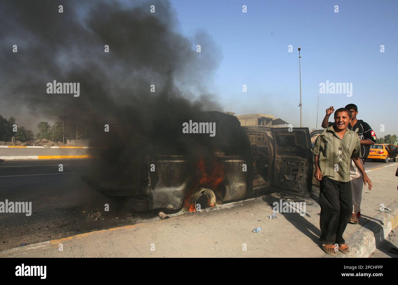 An Iraqi boy reacts in front of a burning vehicle, in Baghdad, Iraq ...