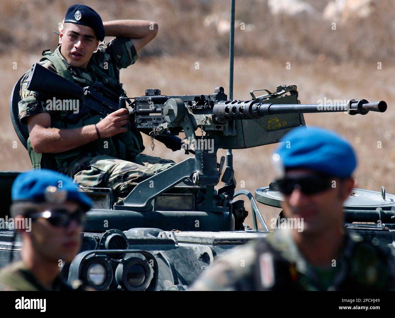 A Lebanese soldier sitting atop an armored personnel patrols past two ...