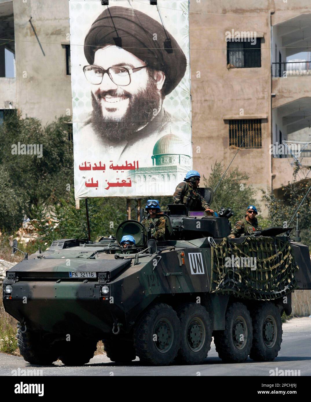 Spanish U.N. peacekeepers patrol past a poster of Hezbollah leader ...
