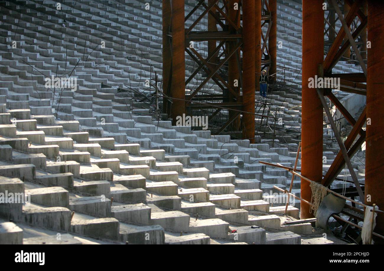 Chinese workers looks up at the steel structure of the Olympic stadium ...