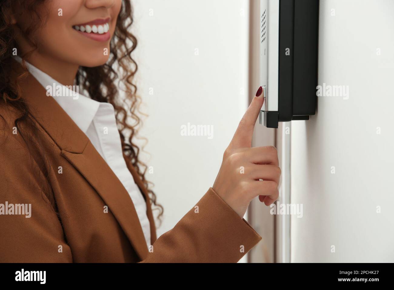 African-American woman pushing intercom button in entryway, closeup ...