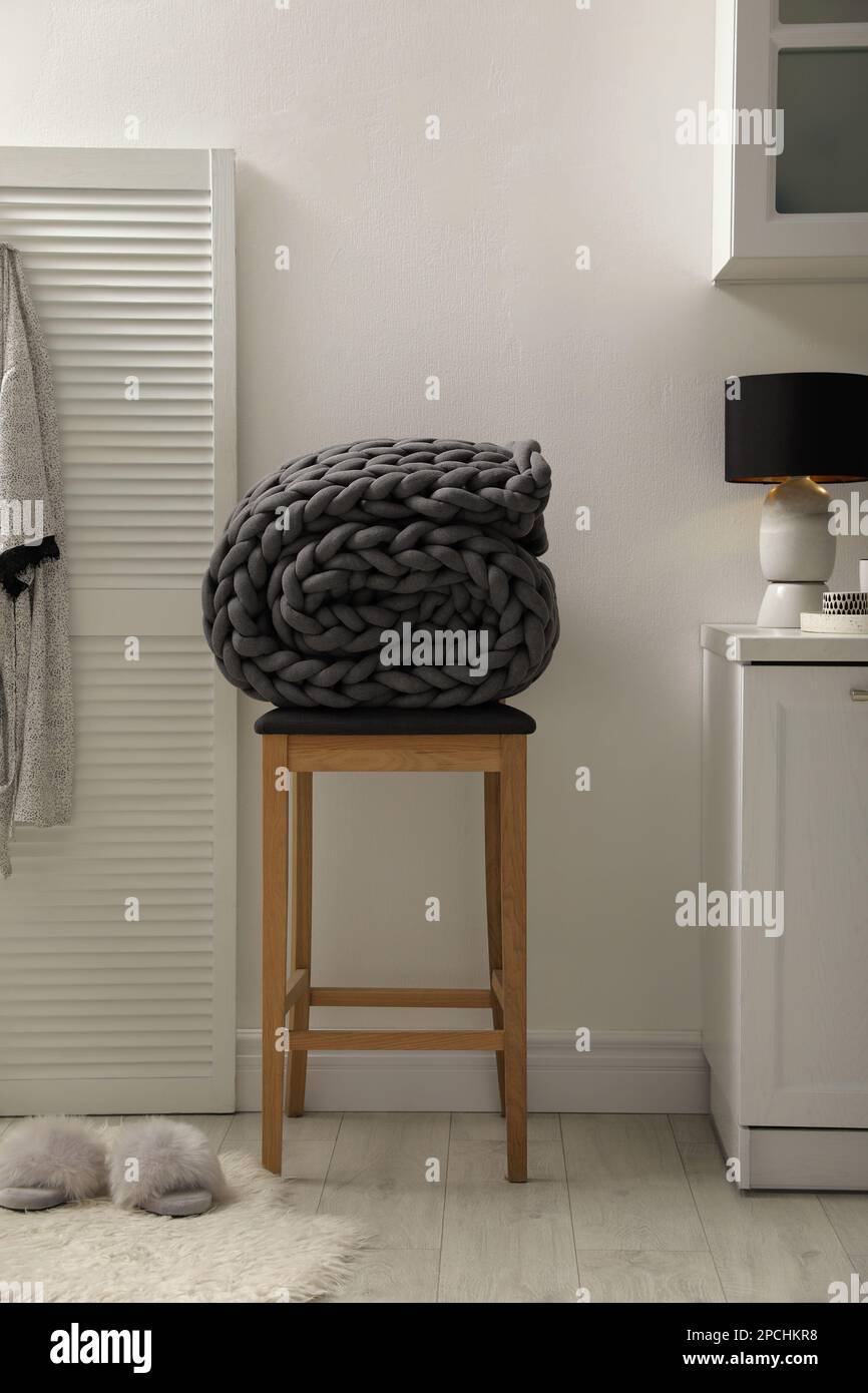 Wooden stool with rolled chunky knit blanket in room Stock Photo - Alamy