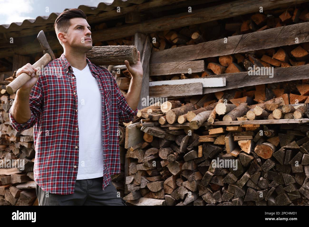 Man with ax and log near wood pile outdoors Stock Photo - Alamy