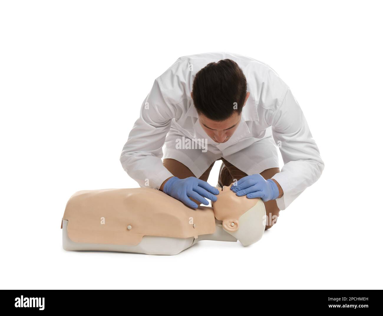 Doctor in uniform practicing first aid on mannequin against white ...