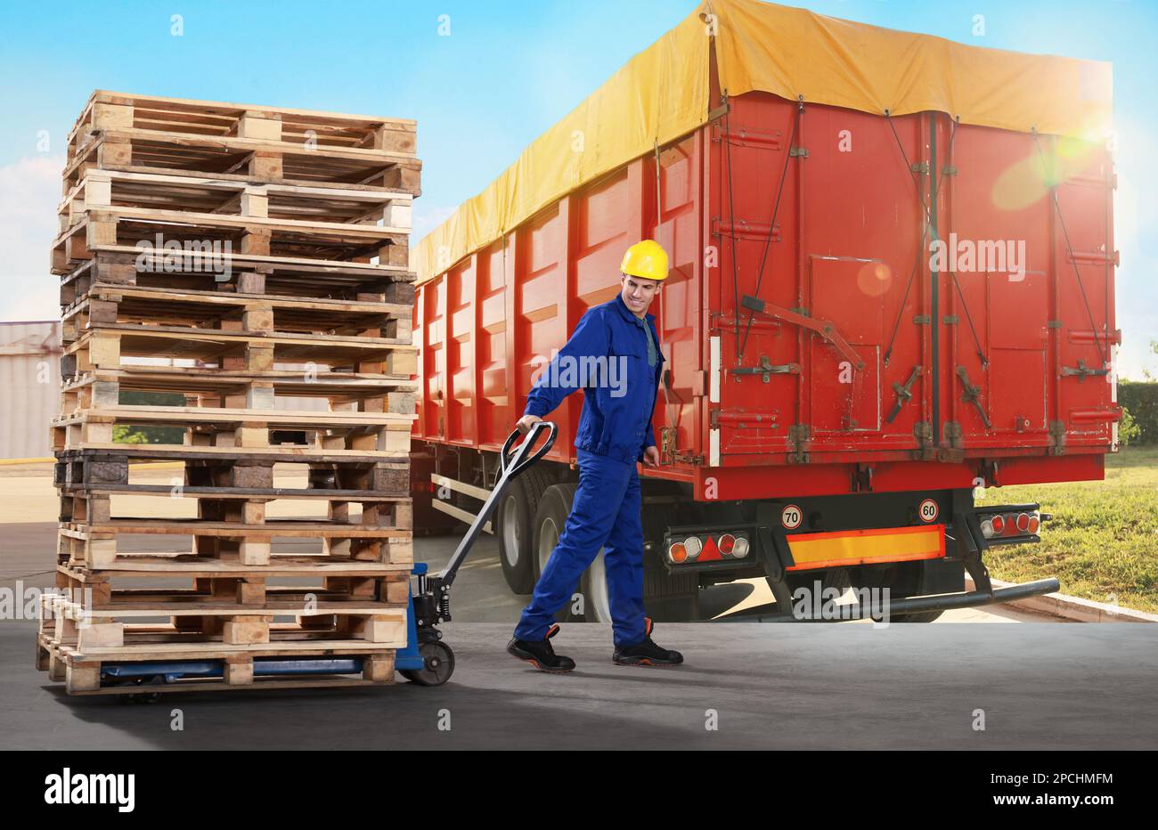 Worker moving wooden pallets with manual forklift and modern truck ...