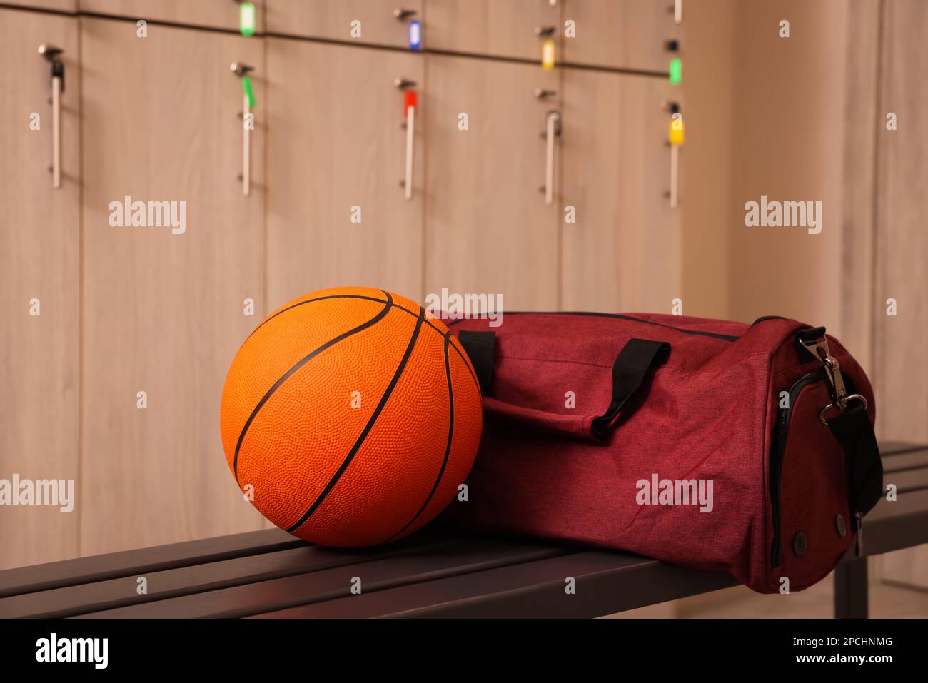 Sports bag and basketball ball on wooden bench in locker room Stock ...