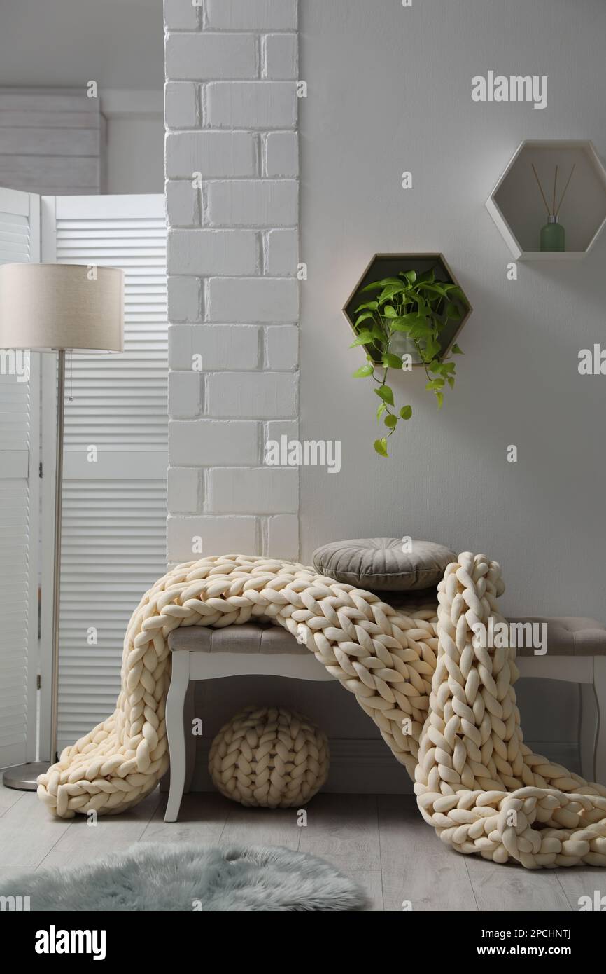 Indoor bench with soft chunky knit blanket, cushion and pouf in room ...