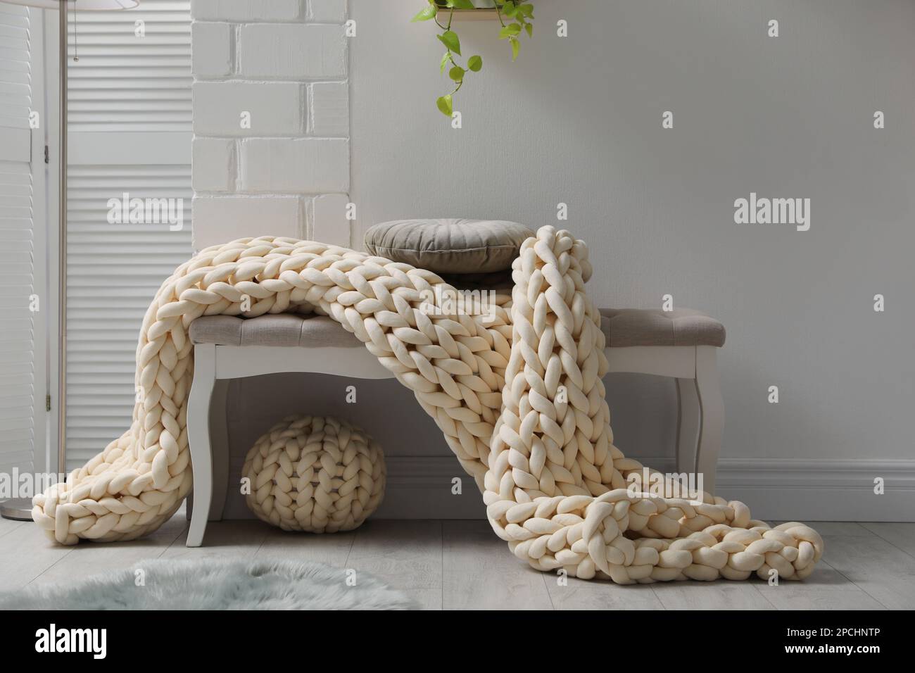 Indoor bench with soft chunky knit blanket, cushion and pouf in room ...
