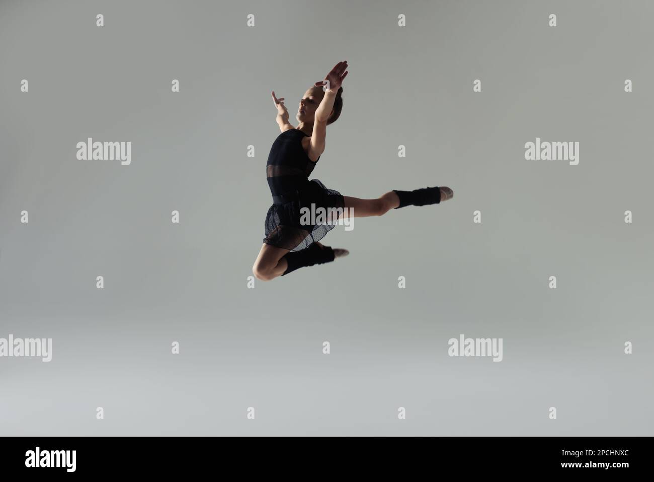 Cute little gymnast doing stag leap on white background Stock Photo - Alamy
