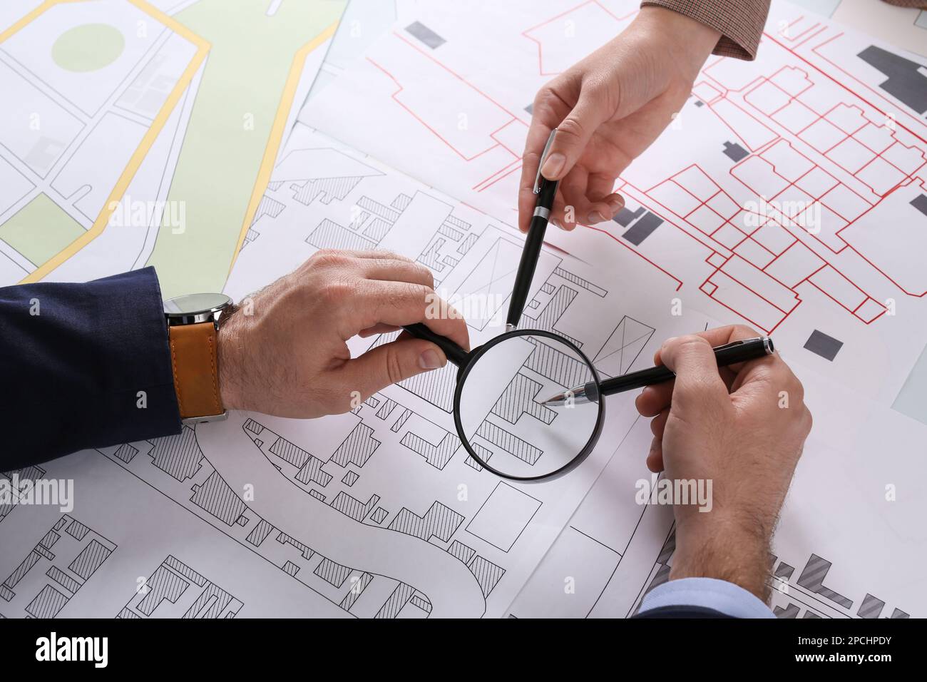 Professional cartographers working with cadastral map at table, closeup ...