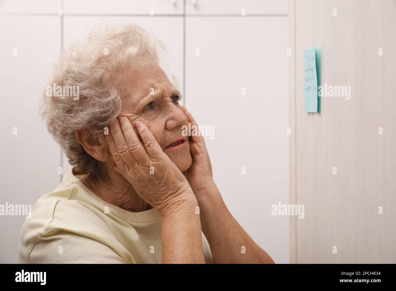 Senior woman looking at reminder note indoors. Age-related memory ...