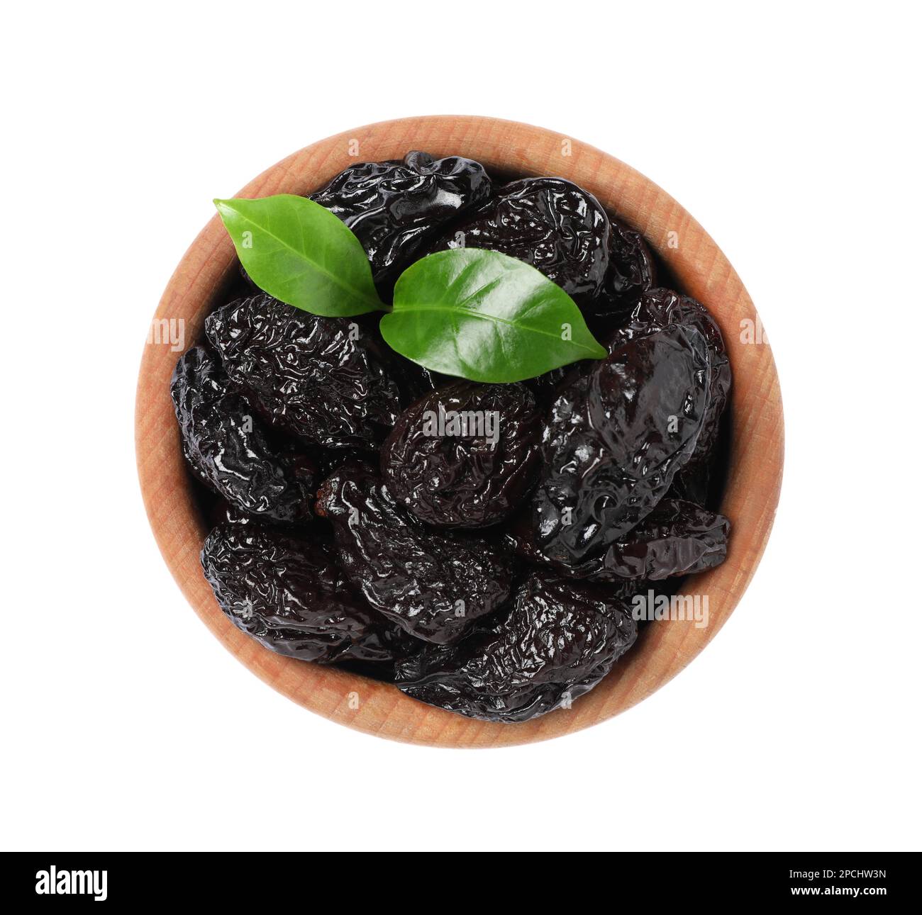Wooden bowl with sweet dried prunes and green leaves isolated on white ...