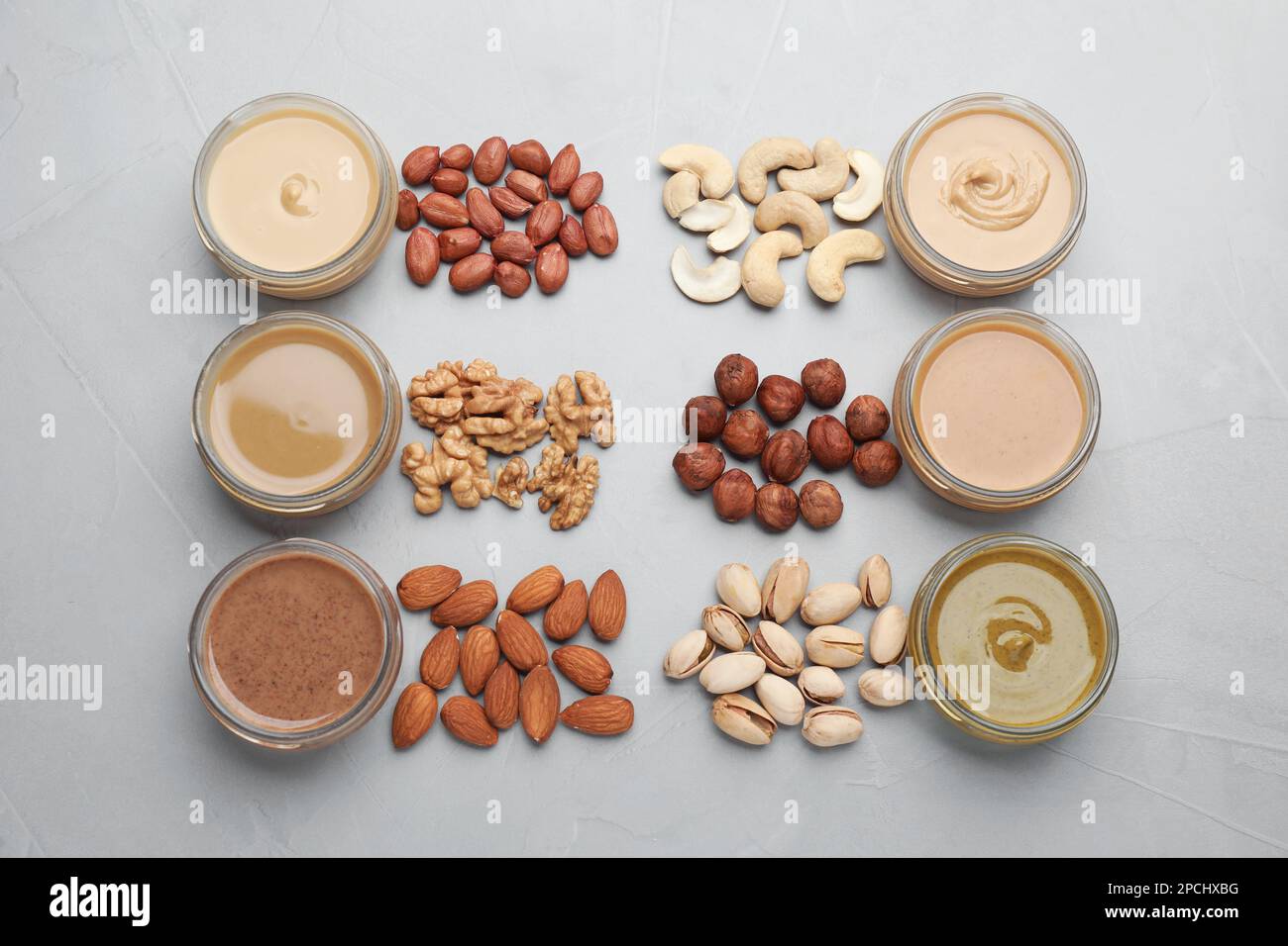 Different types of delicious nut butters and ingredients on grey table ...
