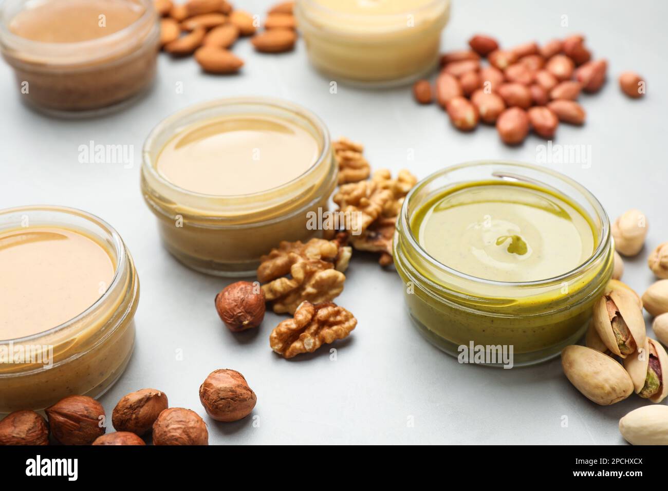 Different types of delicious nut butters and ingredients on light table ...