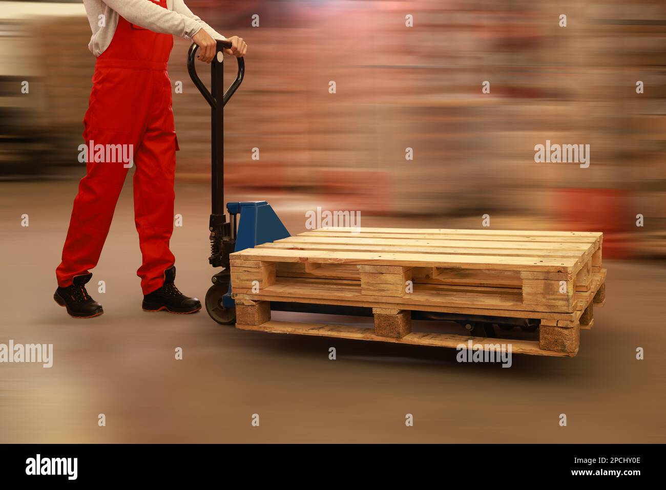 Worker moving wooden pallets with manual forklift in warehouse, closeup ...