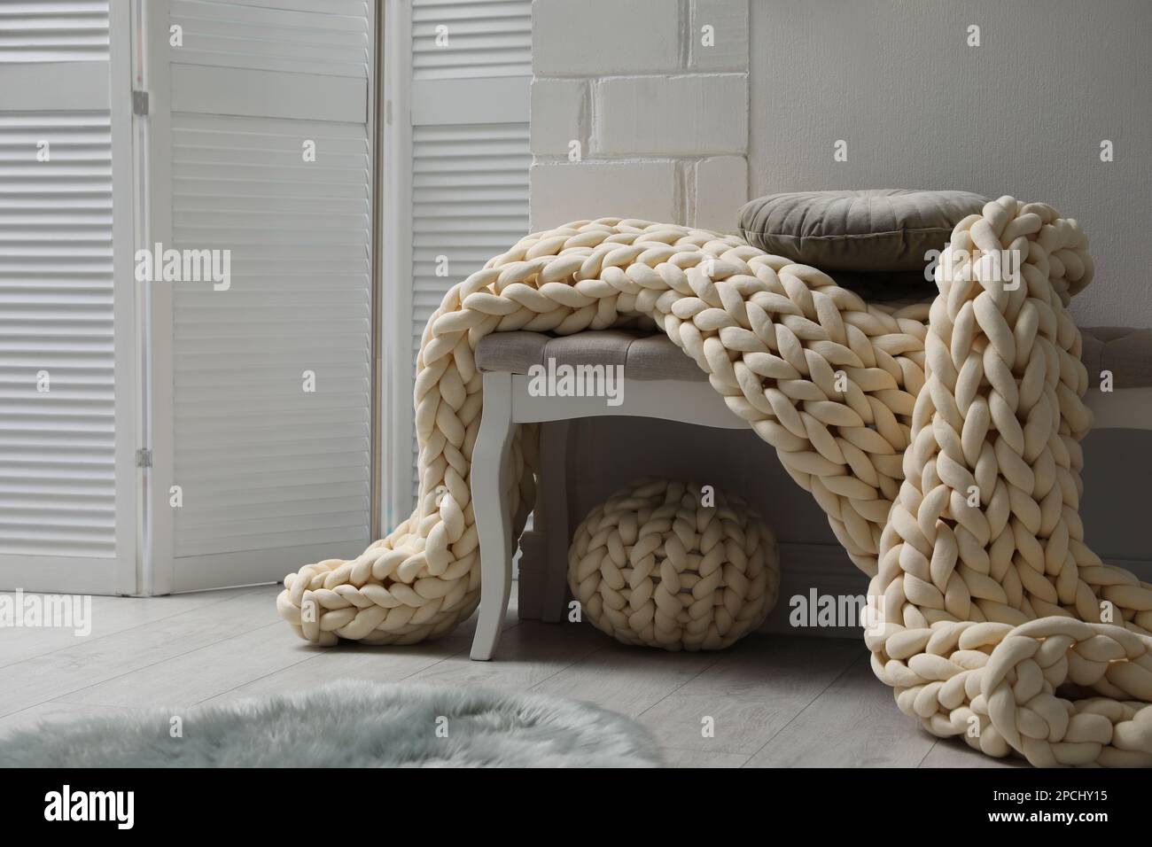 Indoor bench with soft chunky knit blanket, cushion and pouf in room ...
