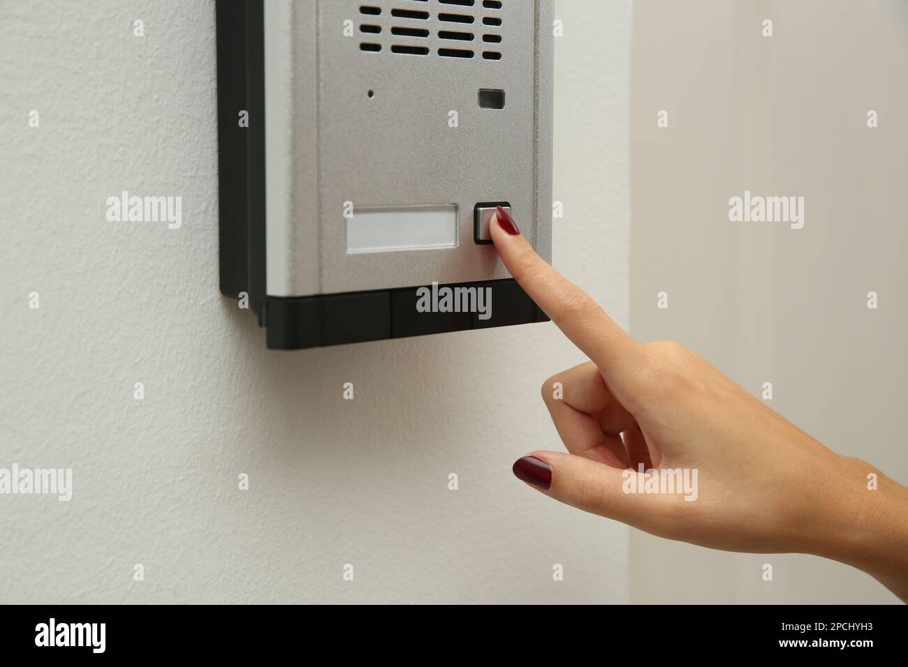 African-American woman pushing intercom button in entryway, closeup ...