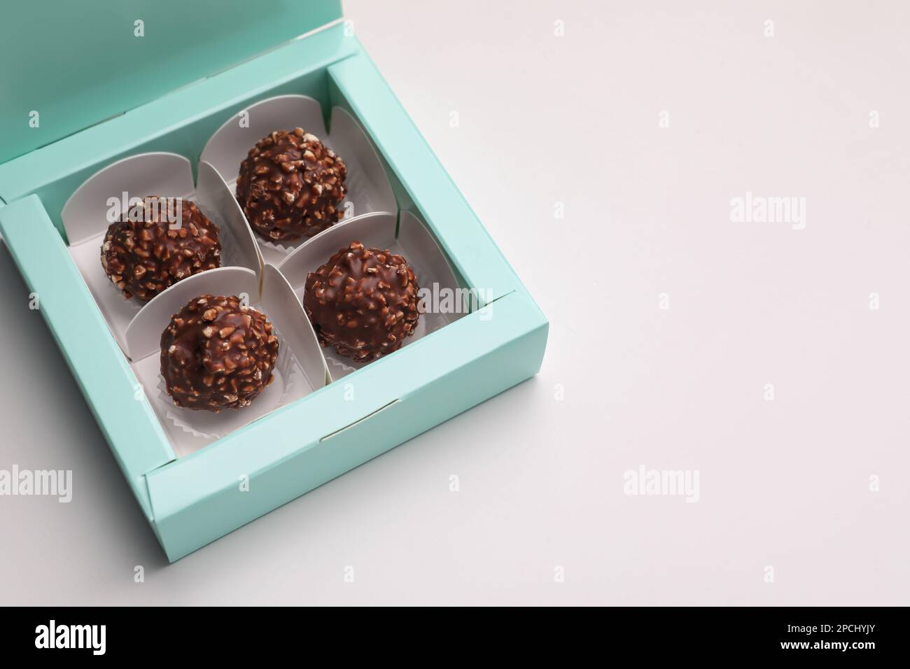 Delicious chocolate candies in turquoise box on light grey background ...