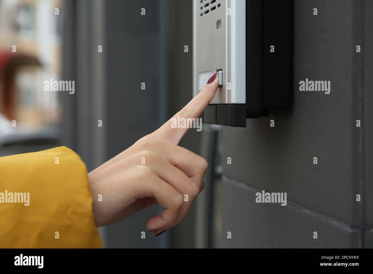 African-American woman ringing intercom with camera near building ...