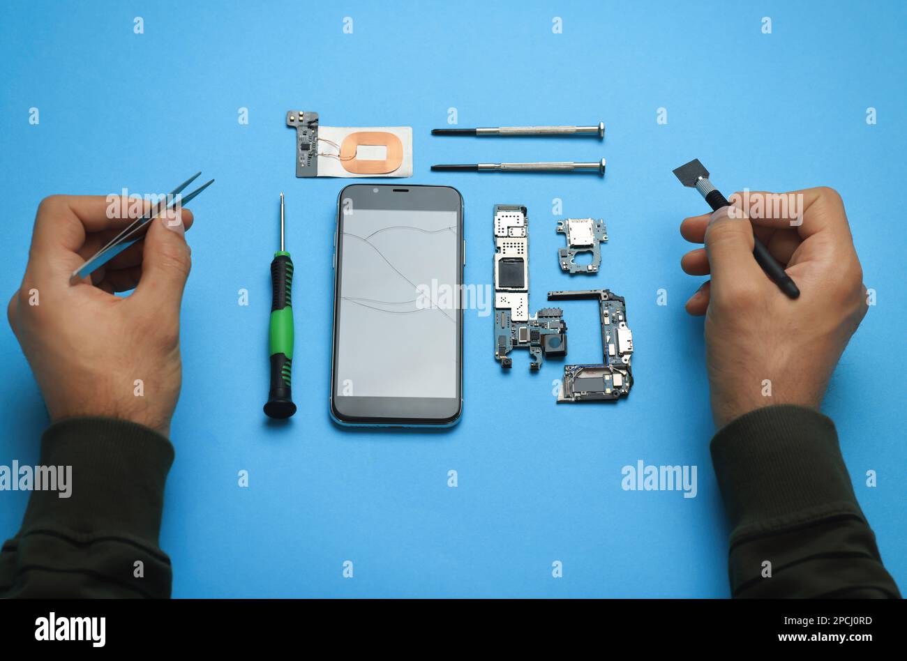Man repairing broken smartphone on light blue background, above view ...