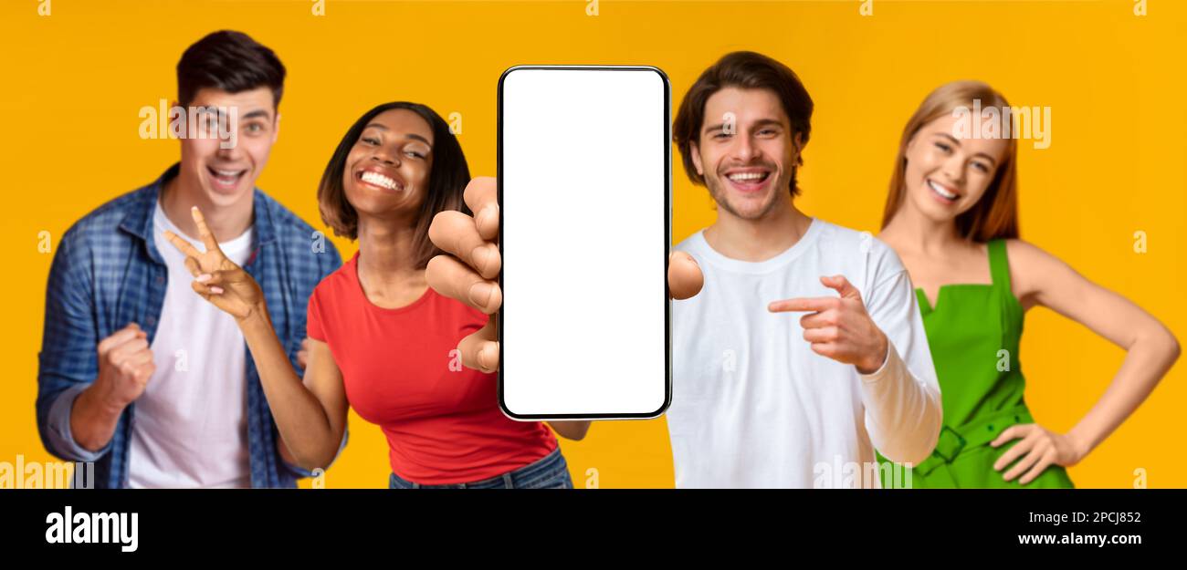 Smiling caucasian, black people point finger at smartphone with blank ...