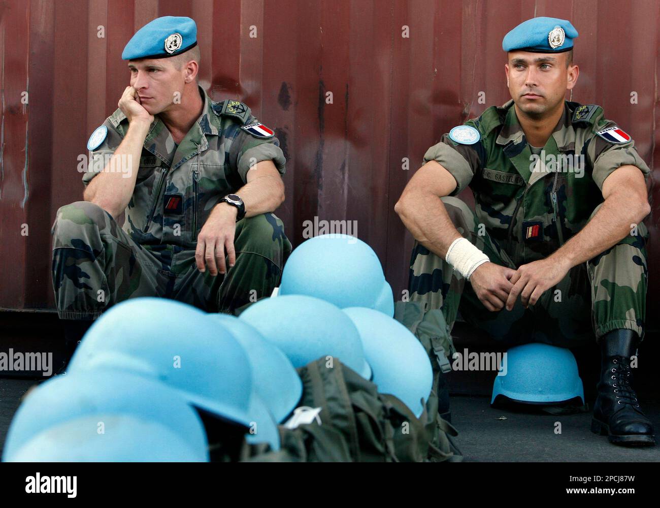 Two French U.N. peacekeepers wait at the dock with their belongings and ...