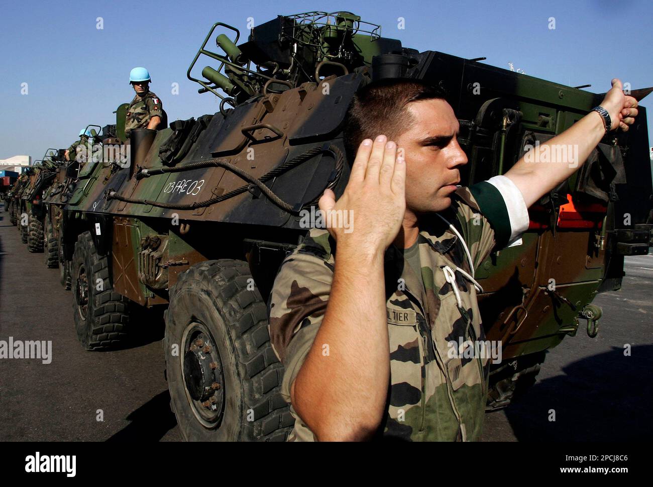 A French U.N. peacekeeper directs a line of armored personnel carriers ...