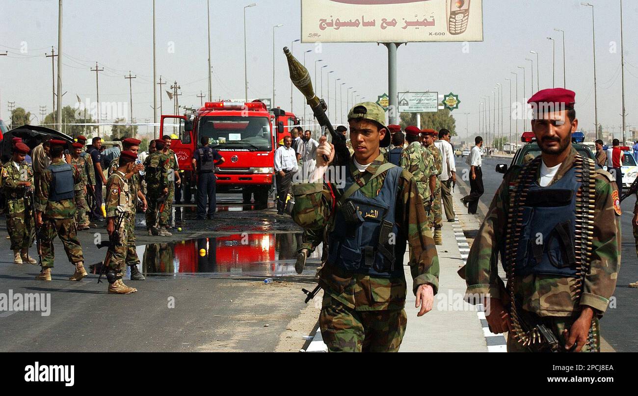 Iraqi army soldiers stand guard at the site of a burnt four-wheel drive ...