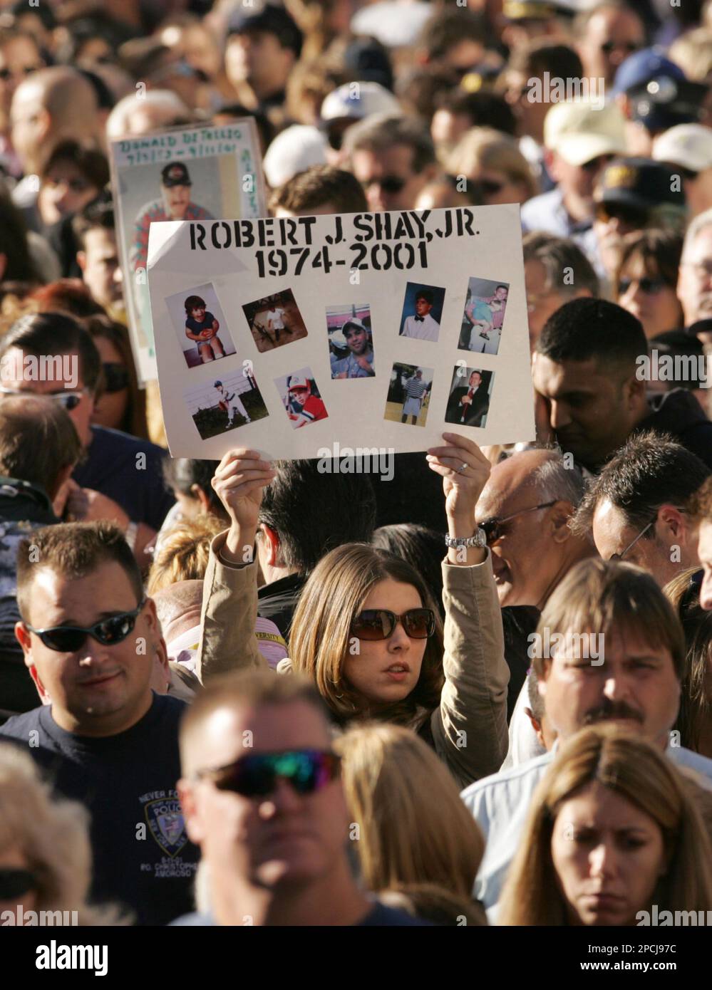 A woman, center, displays a photo of a loved one during a ceremony ...