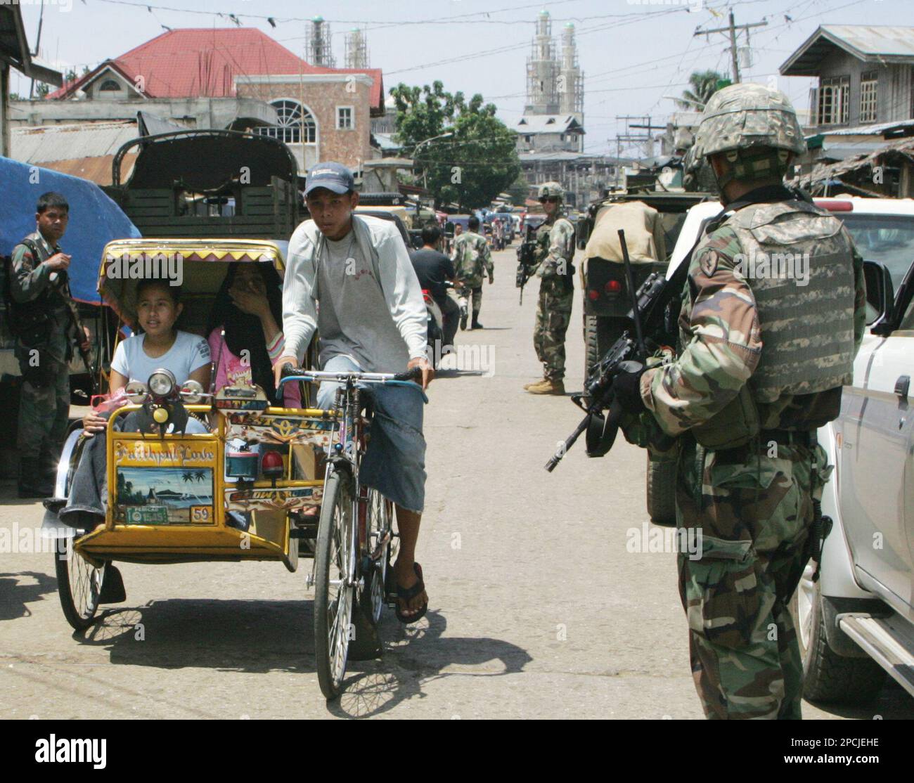 A US Special Forces member, right, watches passing tricycle as he ...