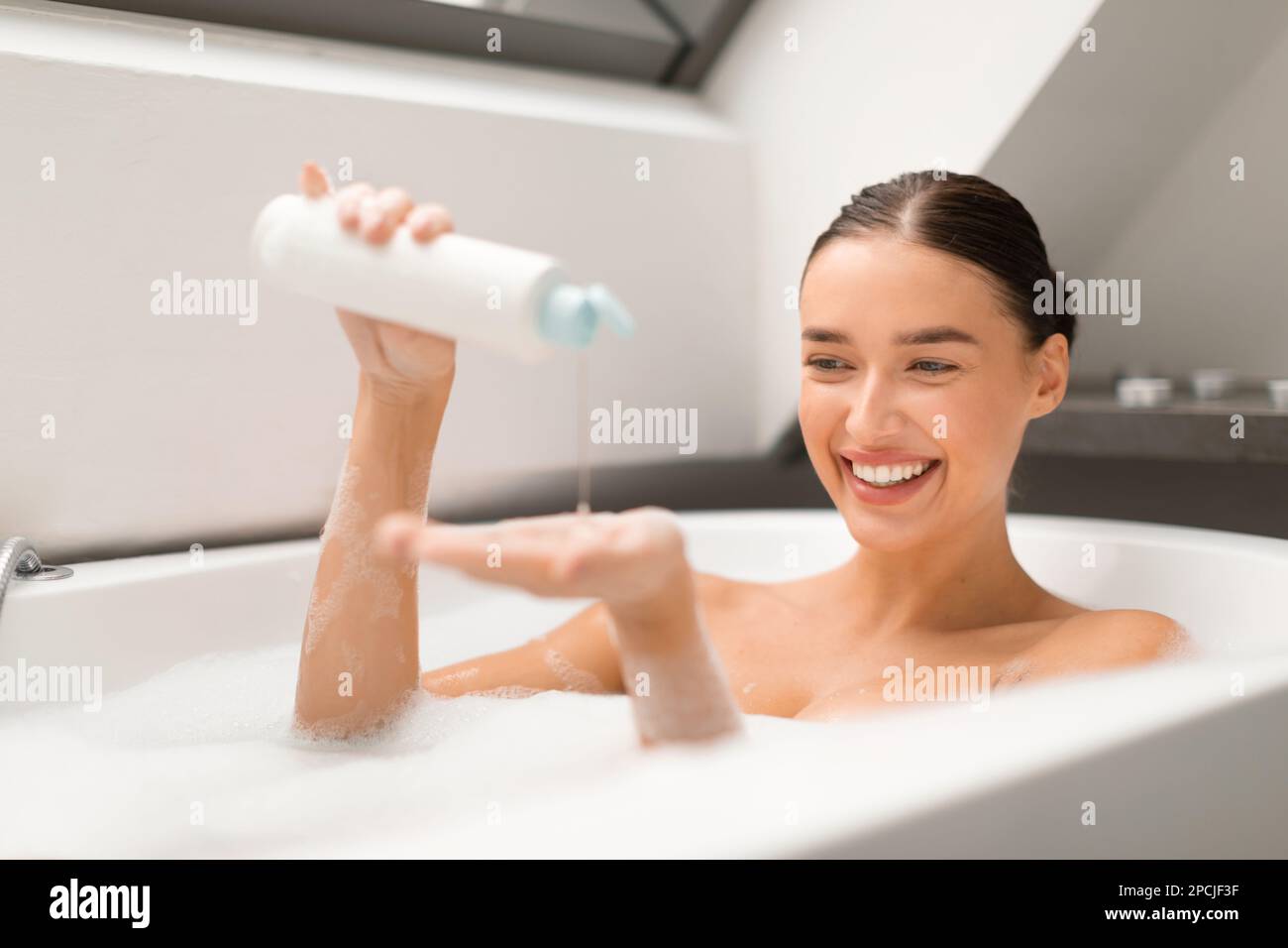 Happy Female Taking Bath Squeezing Shower Gel From Bottle Indoors Stock ...