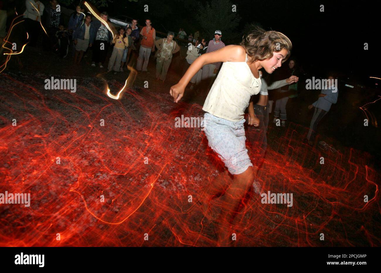 A young Bulgarian girl performs barefoot over smouldering embers as a ...