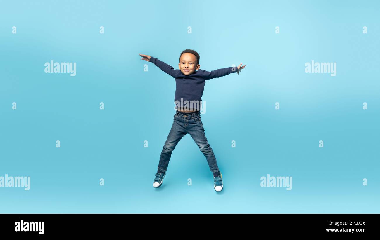 Energetic black boy jumping and raising hands up, having fun and ...