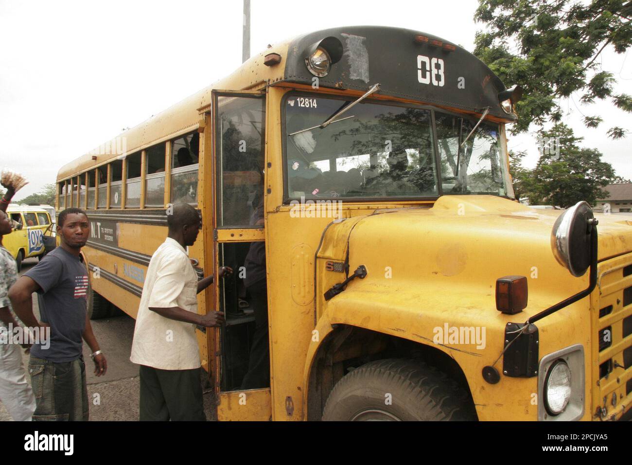 Passengers climb into an old American yellow school bus in Kinshasa ...