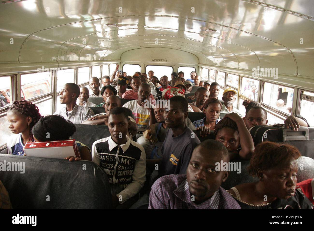 Passengers travel in an old American yellow school bus in Kinshasa ...