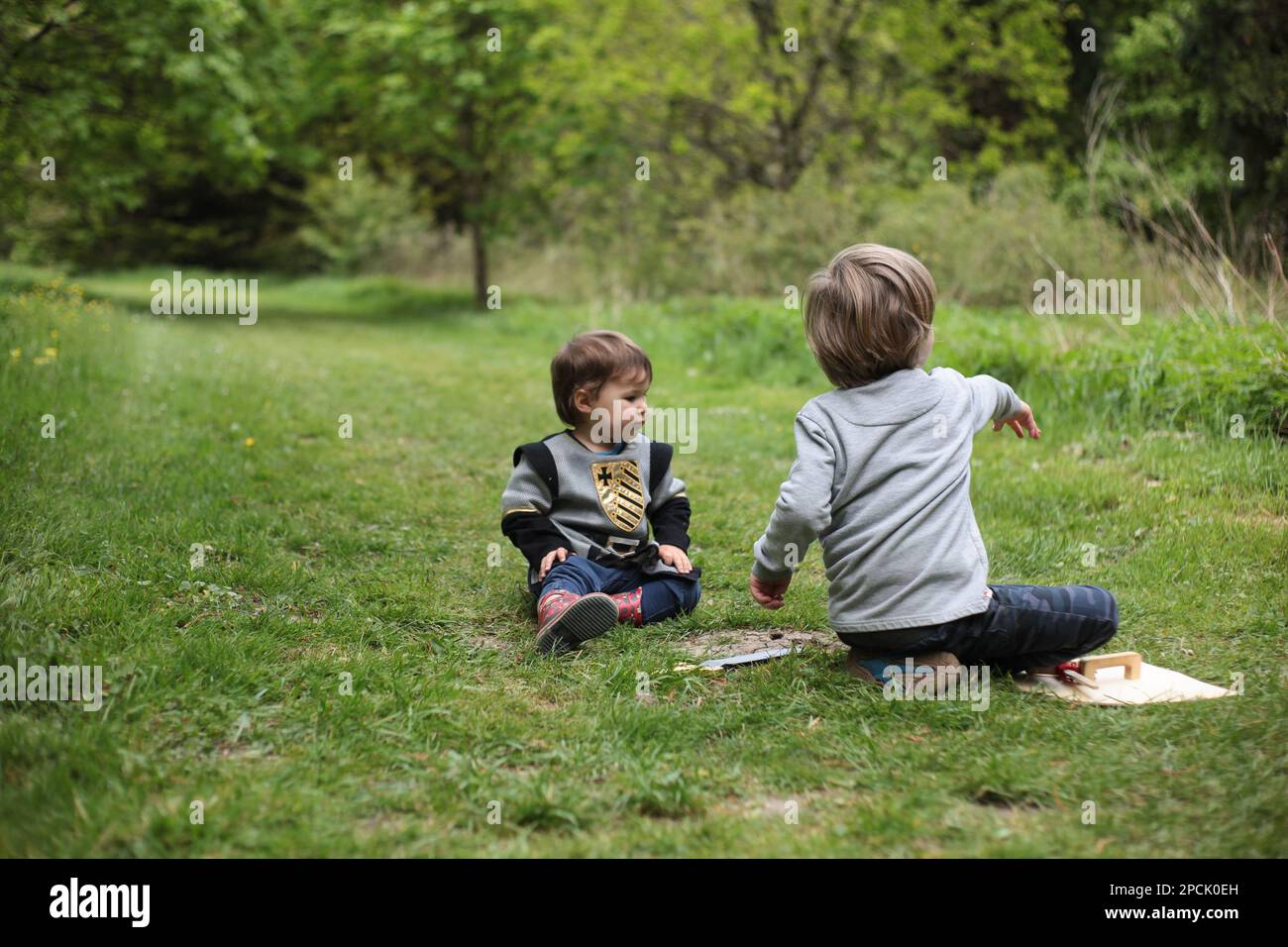 Two children sitting in a meadow Stock Photo - Alamy
