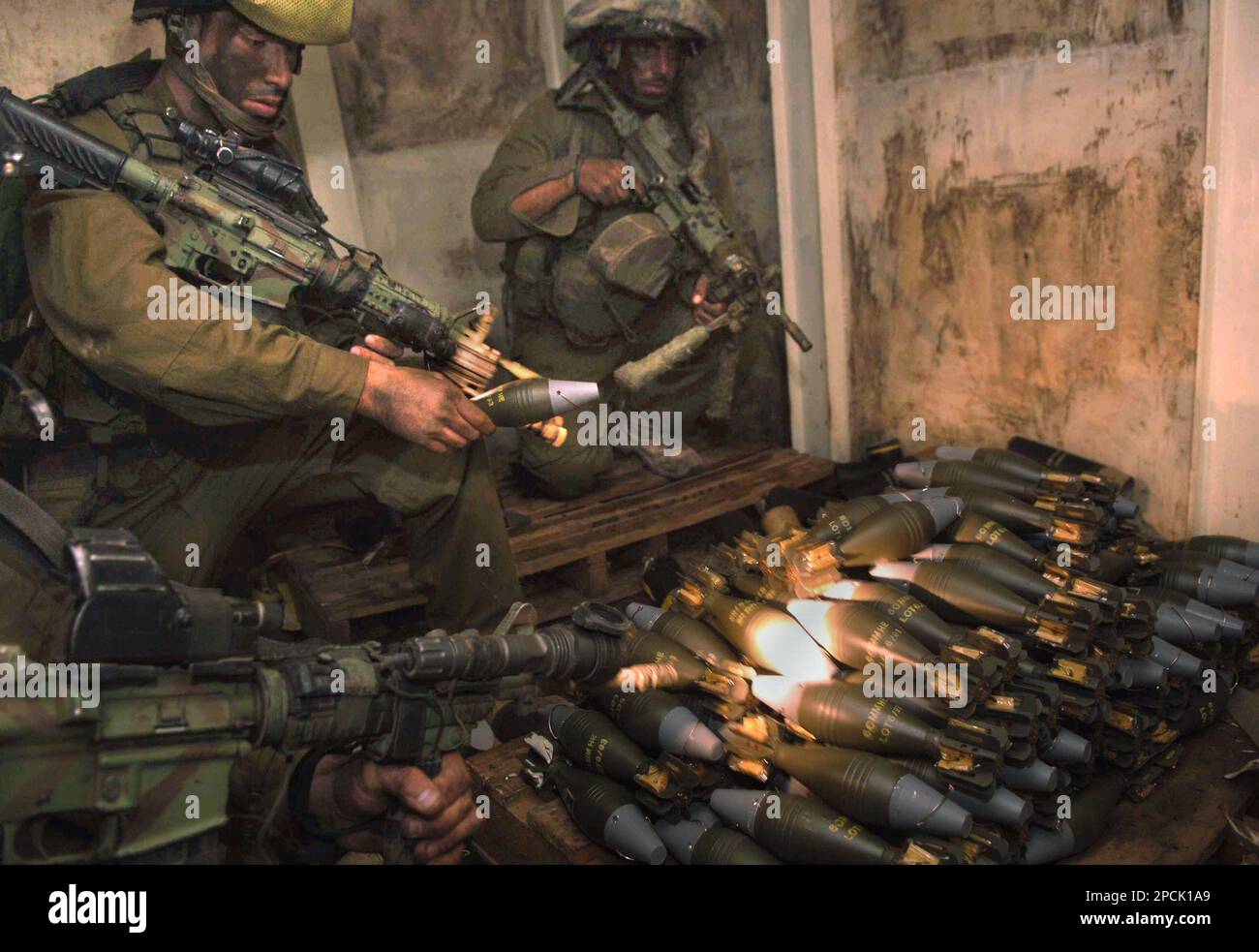 Israeli soldiers look at a pile of mortar shells in a bunker complex ...