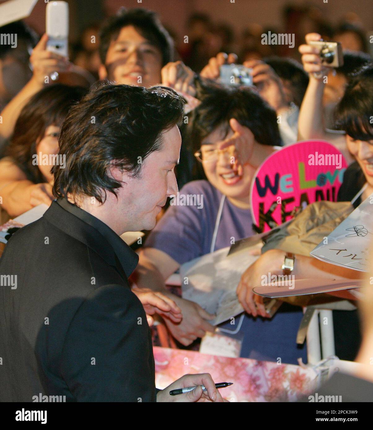 Hollywood star Keanu Reeves gives his autograph to a Japanese fan upon ...